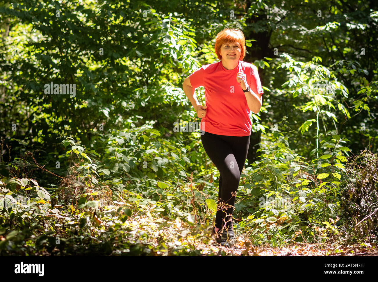 Middle aged women running through a forest Stock Photo - Alamy
