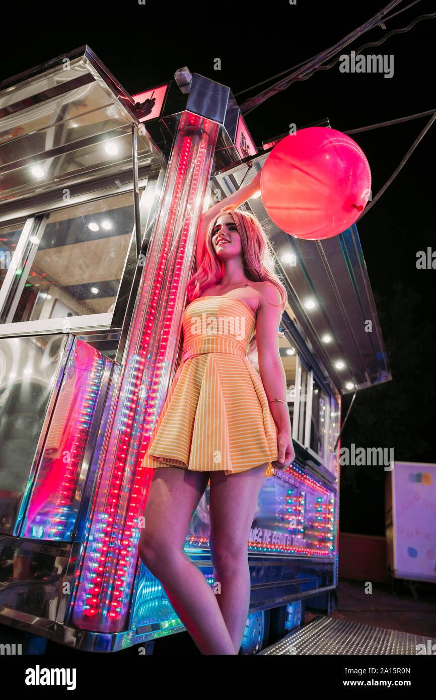 Happy young woman with a balloon on a funfair at night Stock Photo - Alamy