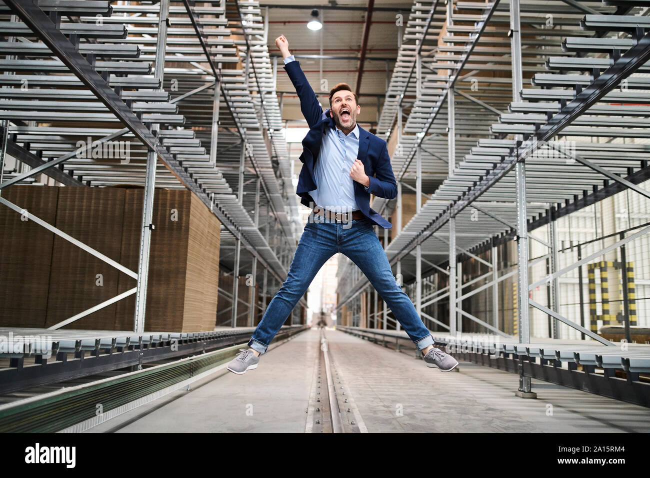 Excited businessman jumping in factory Stock Photo - Alamy