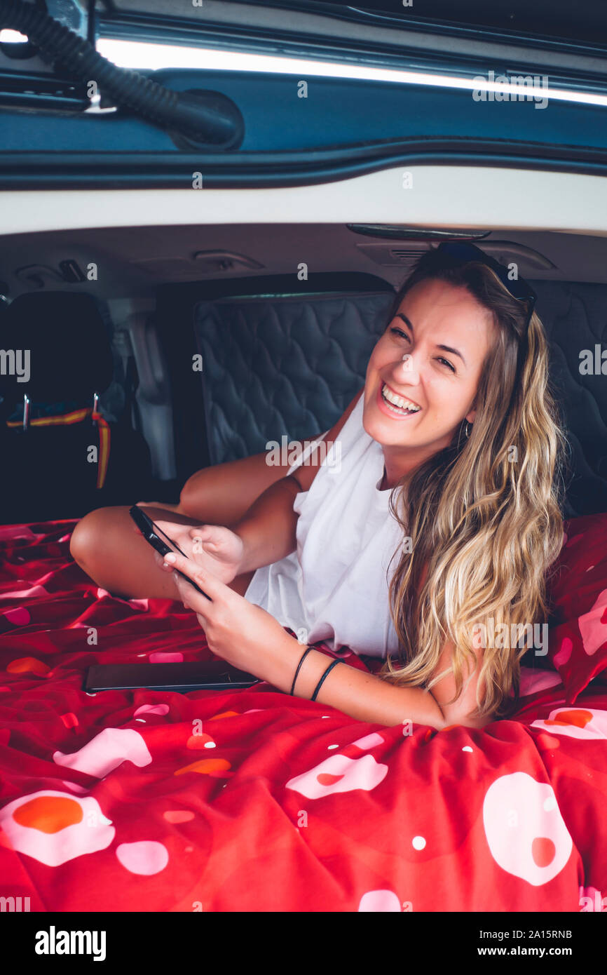 Pretty blond woman camping inside a van using tablet Stock Photo - Alamy