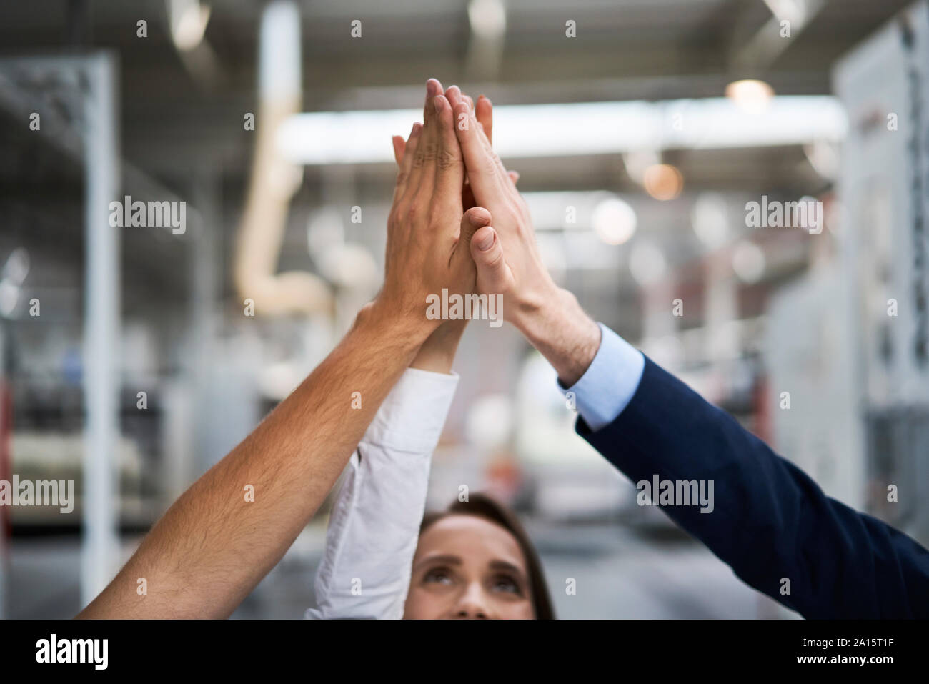Close-upof businessman and employees high fiving in a factory Stock ...