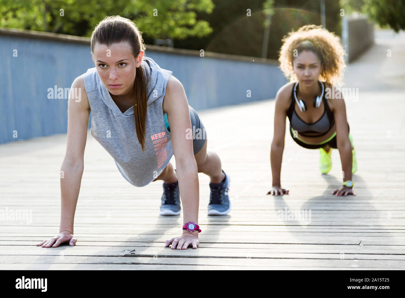 Two sporty young women doing push-ups on a bridge Stock Photo - Alamy