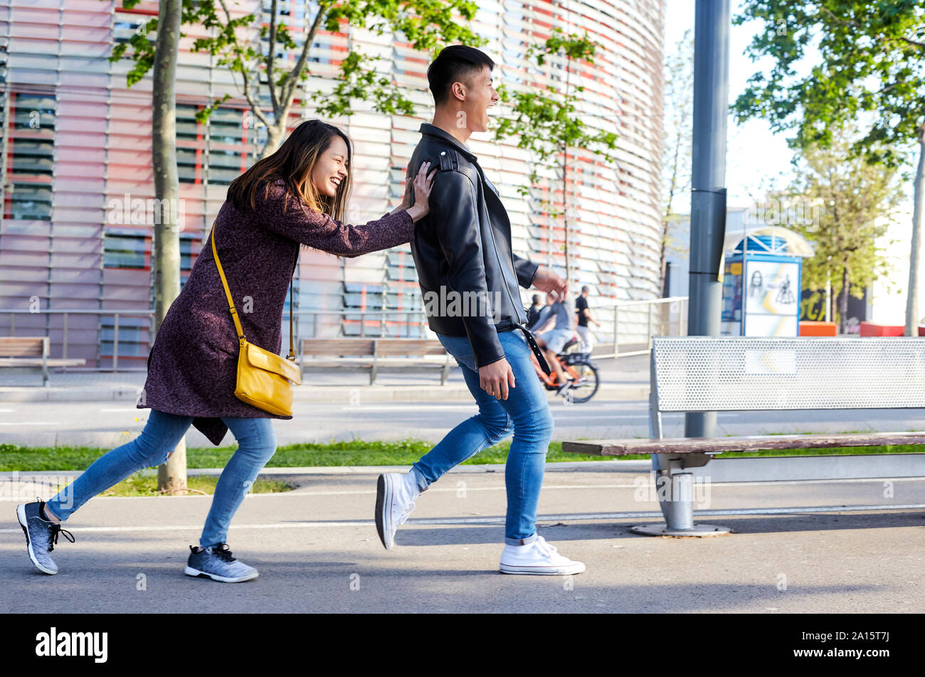 Happy woman pushing boyfriend down the street, Barcelona, Spain Stock ...