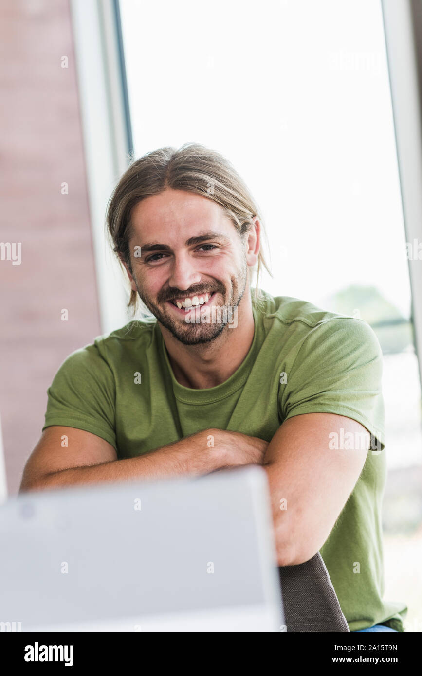 Portrait of happy young businessman sitting in office Stock Photo - Alamy