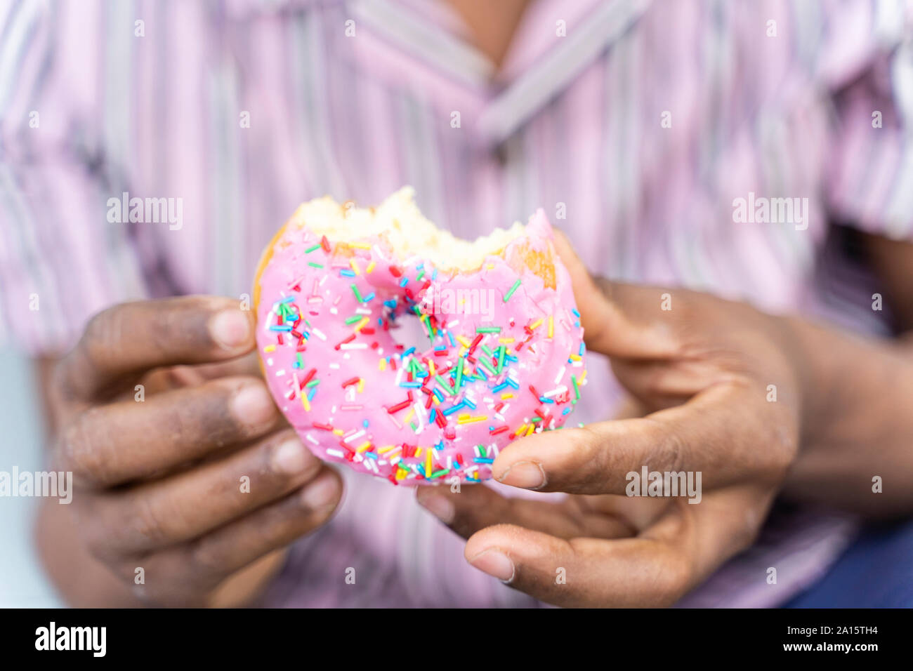 Young man eating donut Stock Photo - Alamy