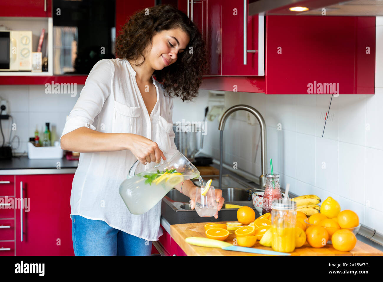 Young woman in kitchen at home pouring lemonade into glass Stock Photo ...
