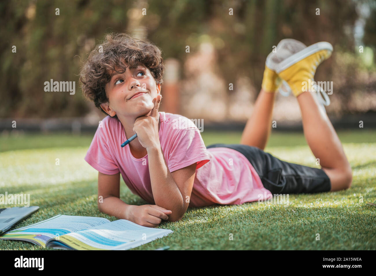 Boy lying in garden doing homework Stock Photo - Alamy