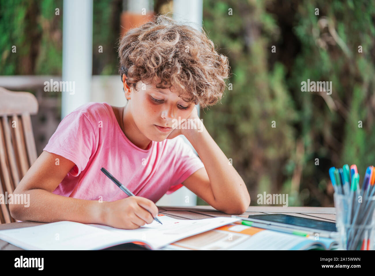 Boy sitting at garden table doing homework Stock Photo - Alamy
