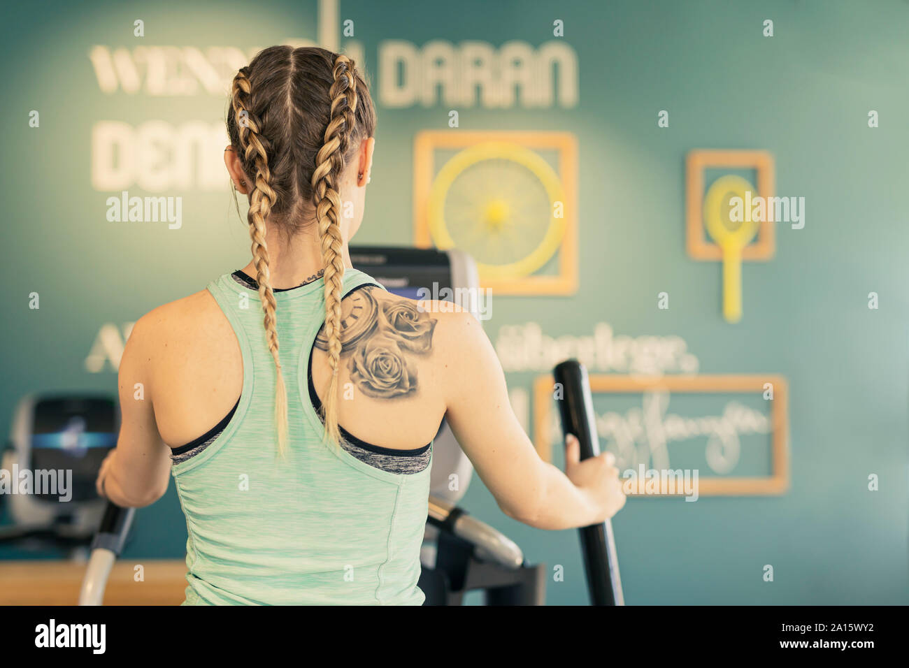 Rear view of young woman exercising on step machine in fitness gym ...