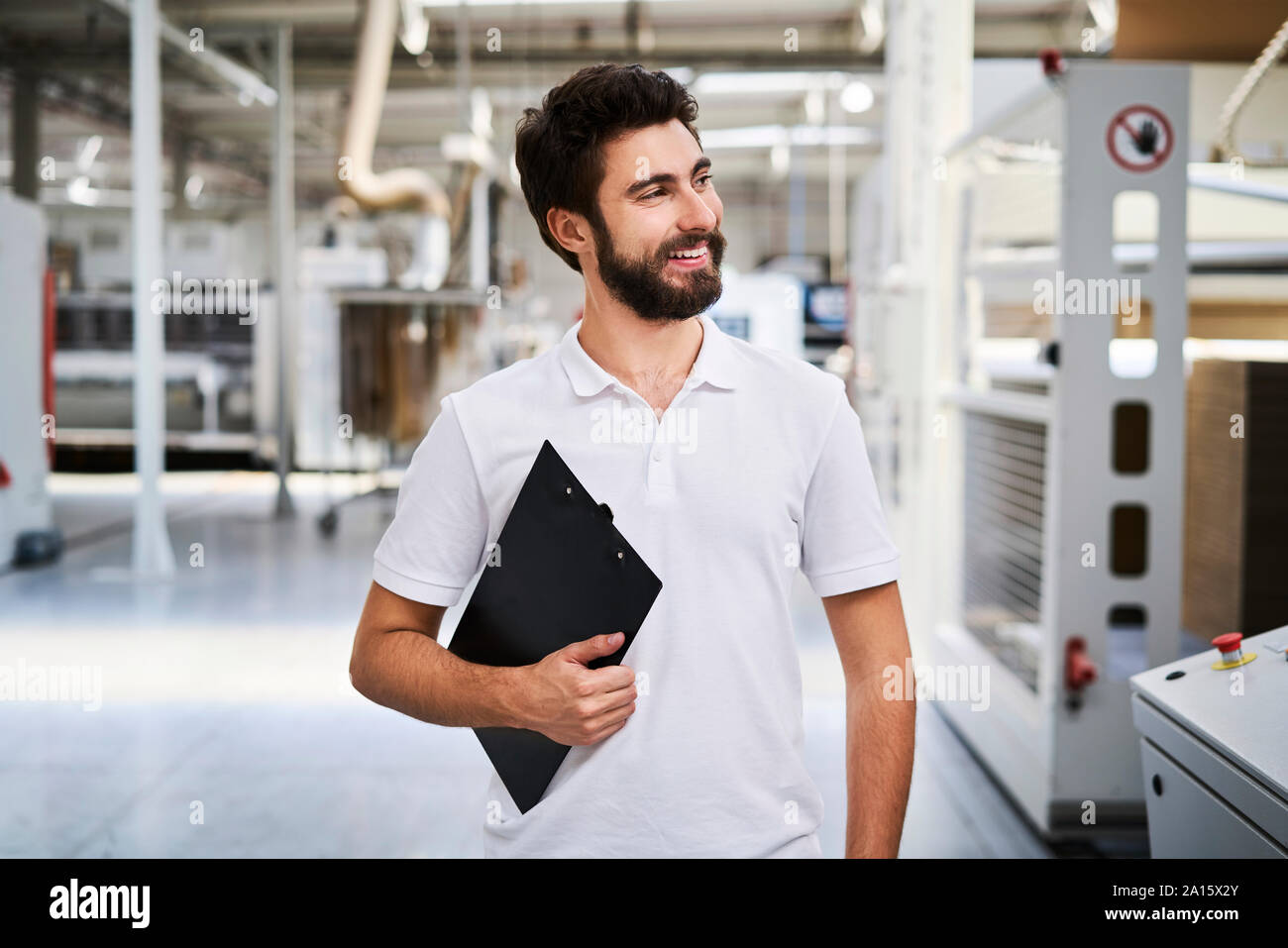 Smiling employee holding clipboard in a factory Stock Photo - Alamy