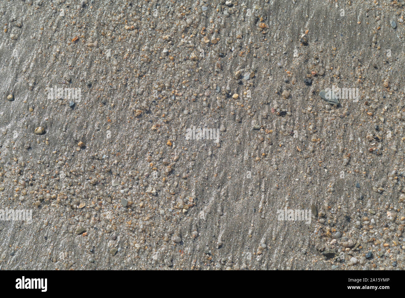 Wet shoreline sand and pebbles left behind as the tide recedes Stock ...