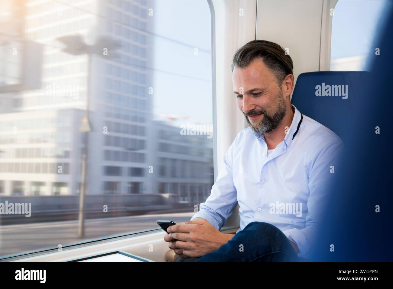 Mature man sitting in a train, using smartphone Stock Photo - Alamy