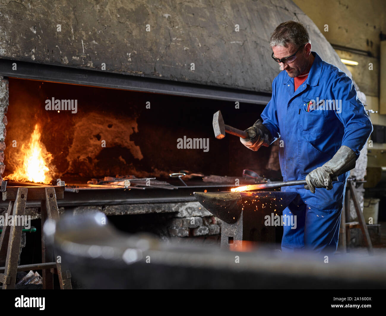 Blacksmith hammering hot iron Stock Photo - Alamy
