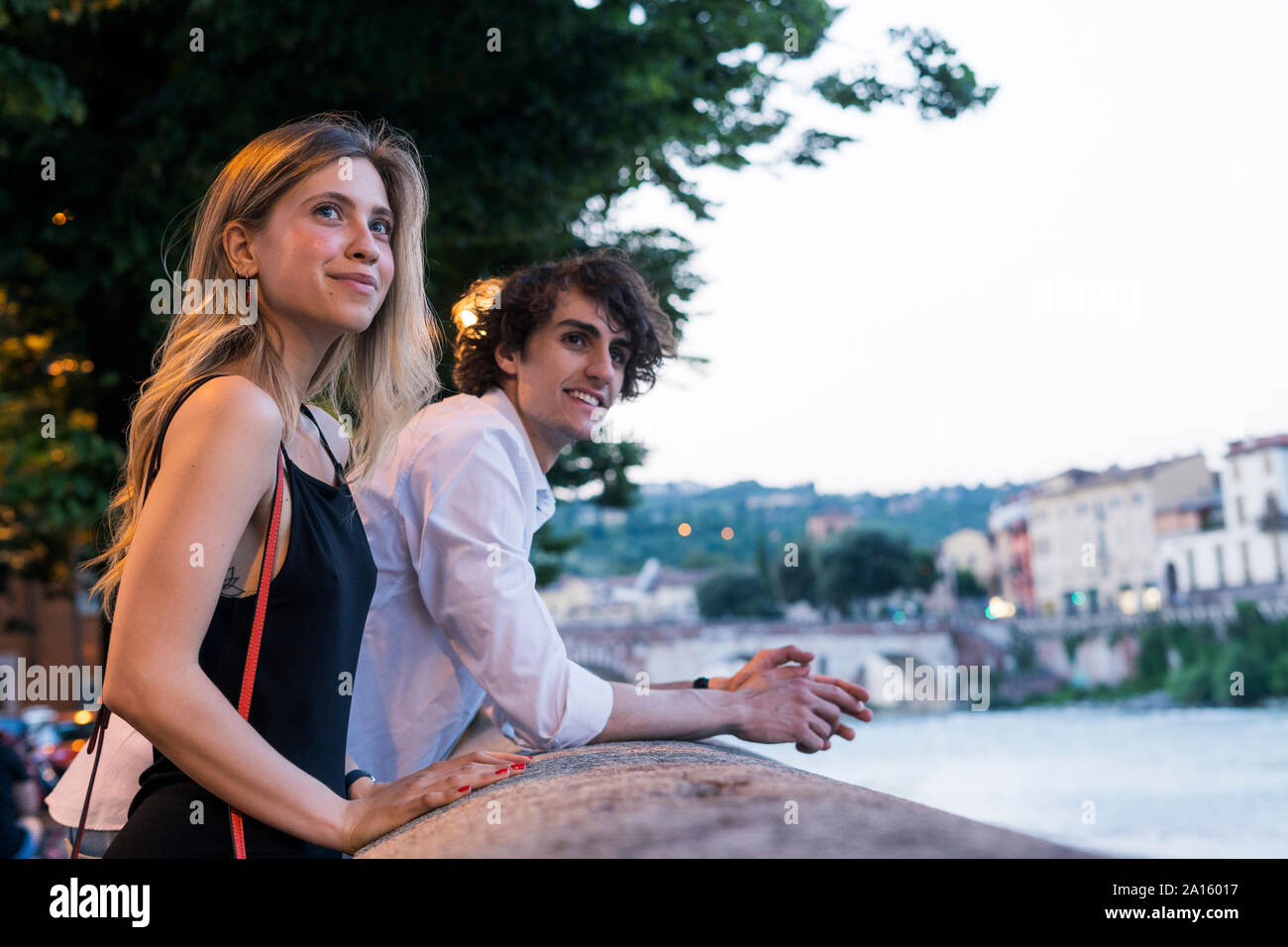 Happy young couple leaning on bridge railing hi-res stock photography ...