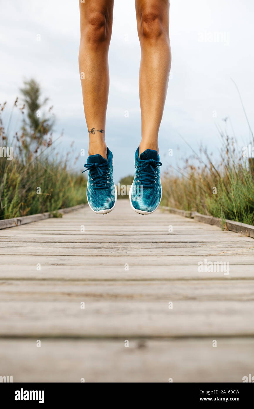 Feet of female jogger, jumping on a wooden walkway Stock Photo - Alamy