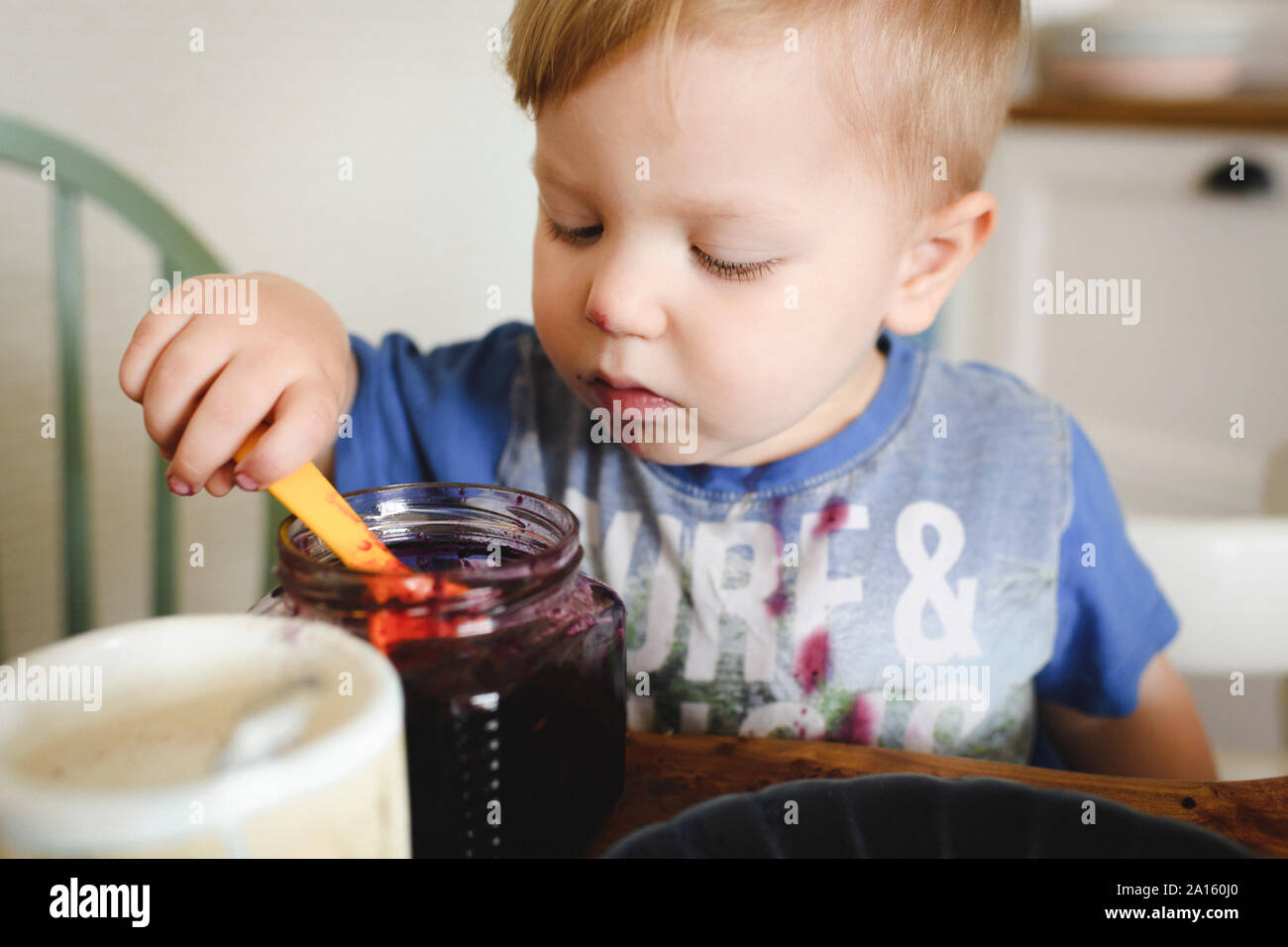Cute little boy eating blueberry jam Stock Photo - Alamy