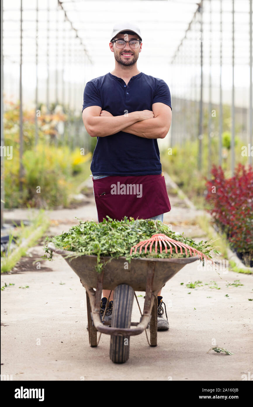 Portrait of young man with wheelbarrow in the greenhouse Stock Photo ...