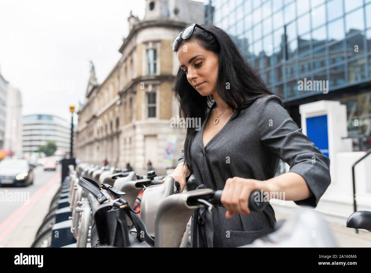 Woman in the city using bicycle hire for commuting hi-res stock ...