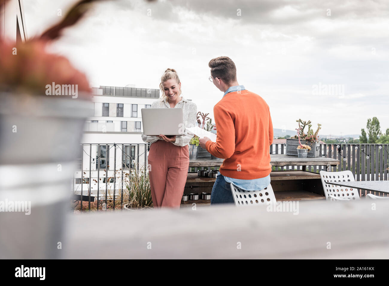 Casual businessman and woman with laptop meeting on roof terrace Stock ...