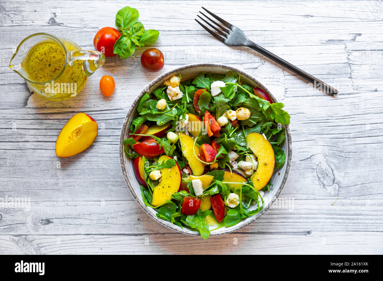 Directly above view of fresh salad in bowl by pitcher and fork on table ...