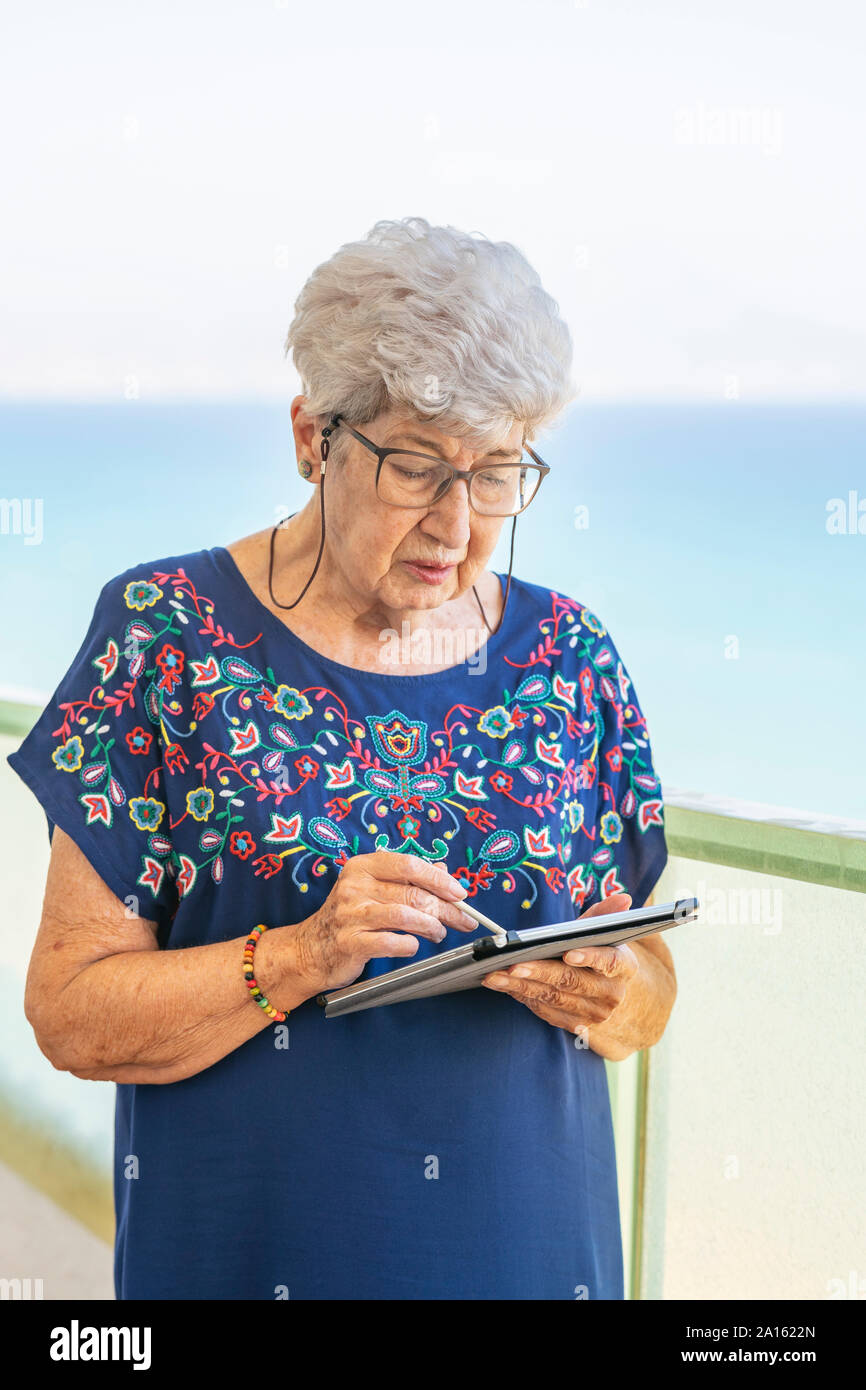 Senior woman using a tablet on a terrace Stock Photo - Alamy