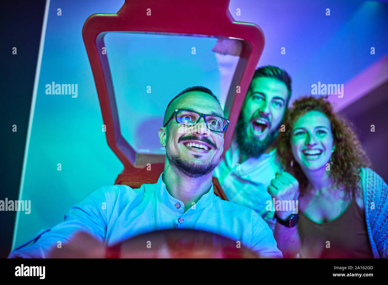 Happy friends playing and having fun with a driving simulator in an ...