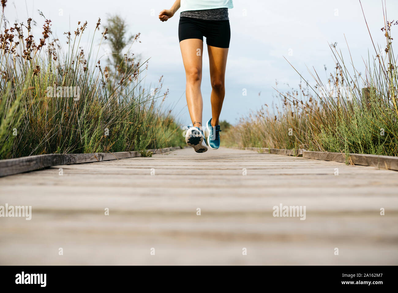 Female jogger running on wooden walkway Stock Photo - Alamy