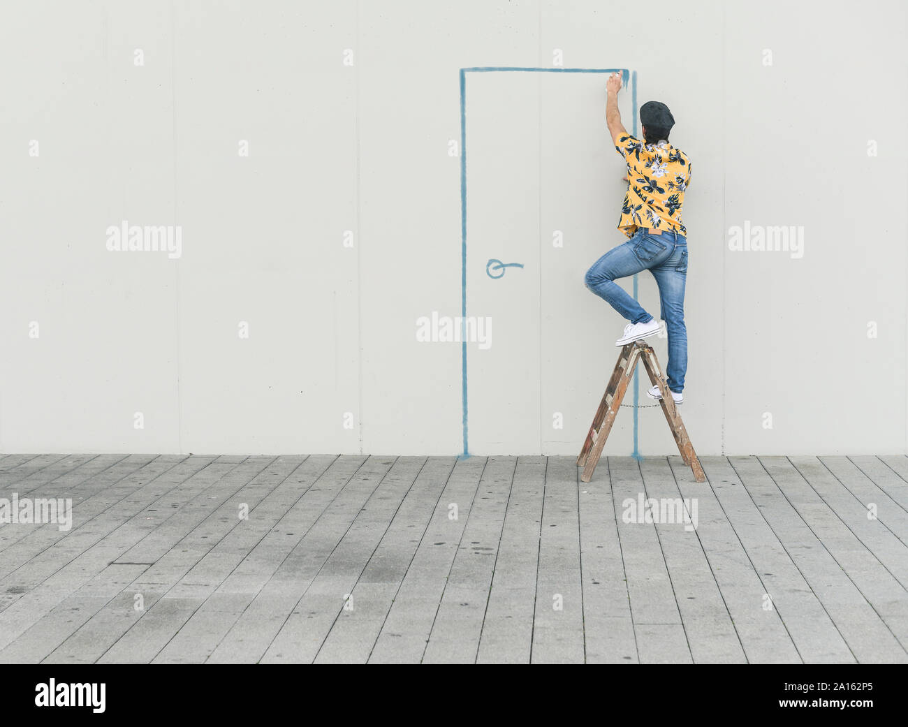 Digital composite of young man drawing a door at a wall Stock Photo - Alamy