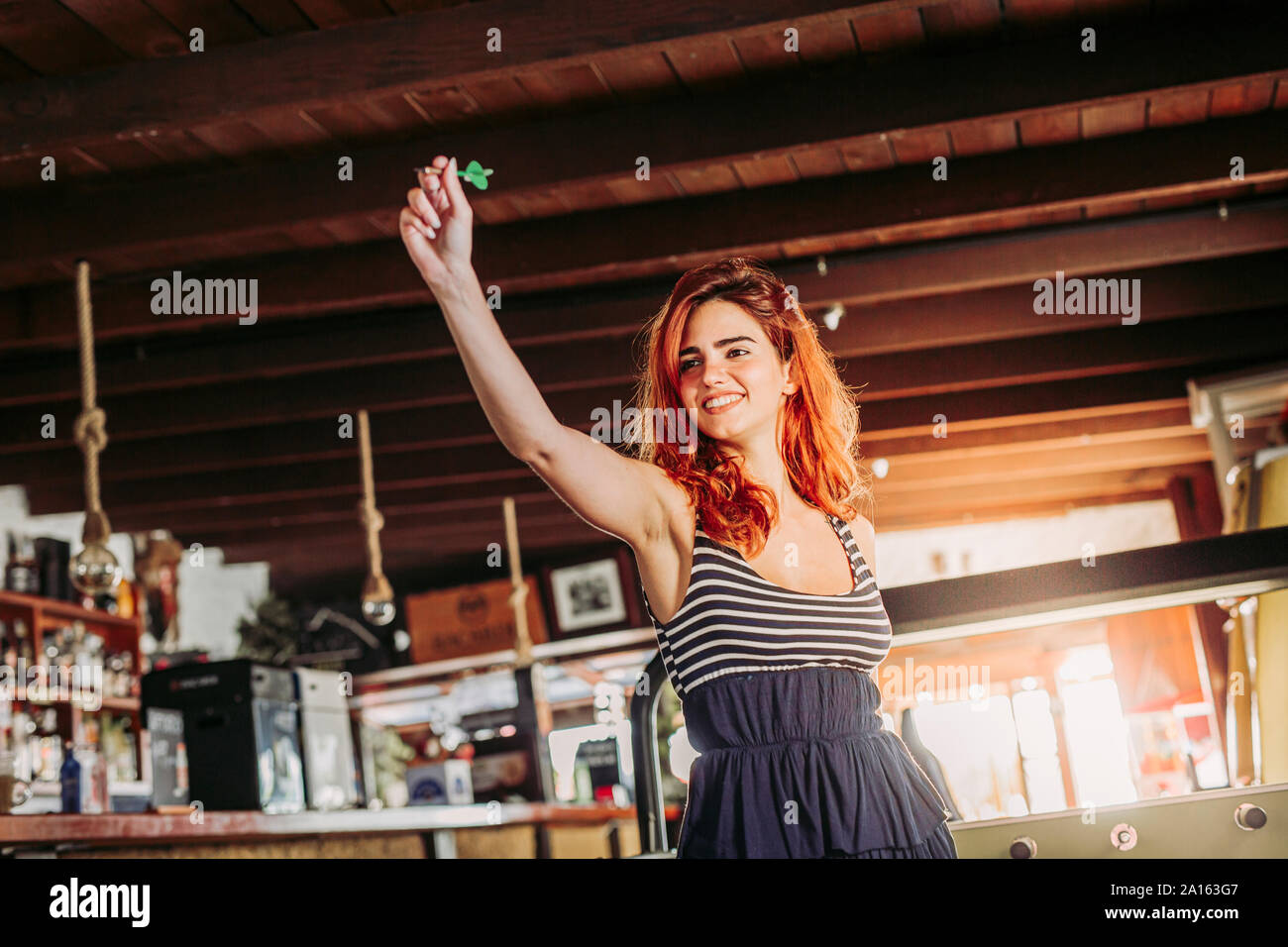 Happy young woman playing darts in a sports bar Stock Photo - Alamy