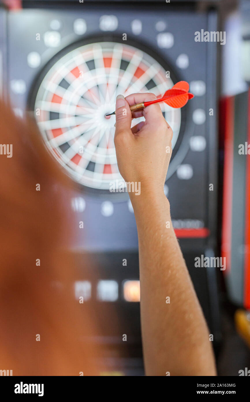 Close-up of woman's hand holding dart in front of dartboard Stock Photo ...