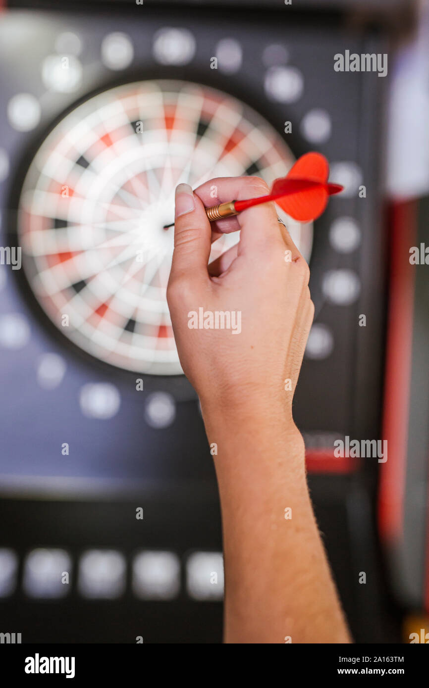 Close-up of woman's hand holding dart in front of dartboard Stock Photo ...