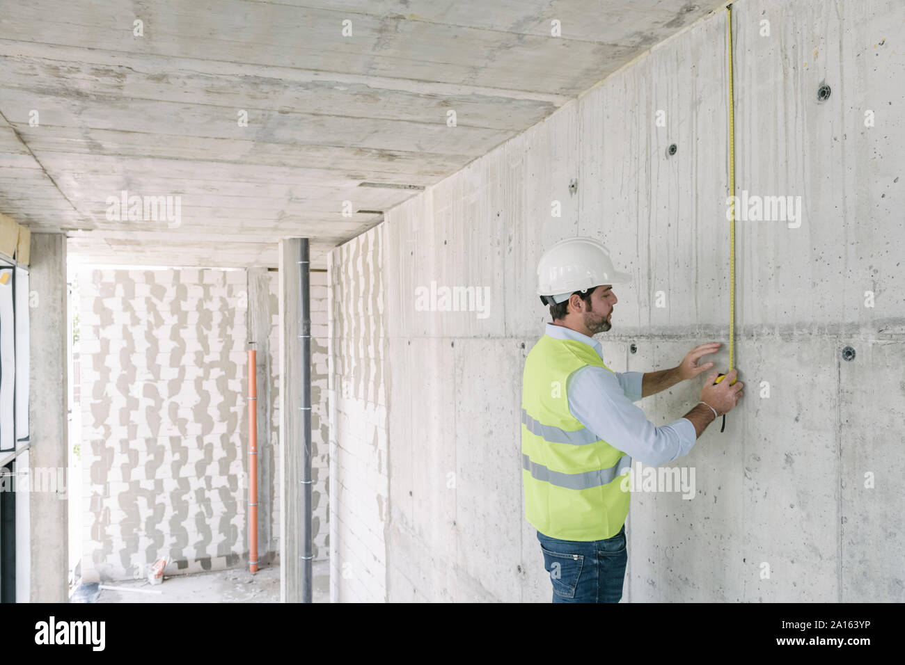 Architect metering a wall at construction site Stock Photo - Alamy