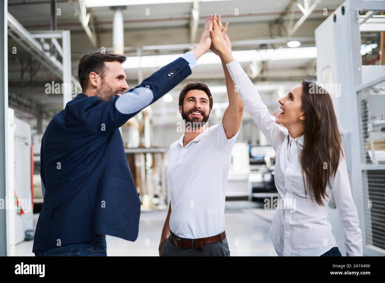 Happy businessman and employees high fiving in a factory Stock Photo ...