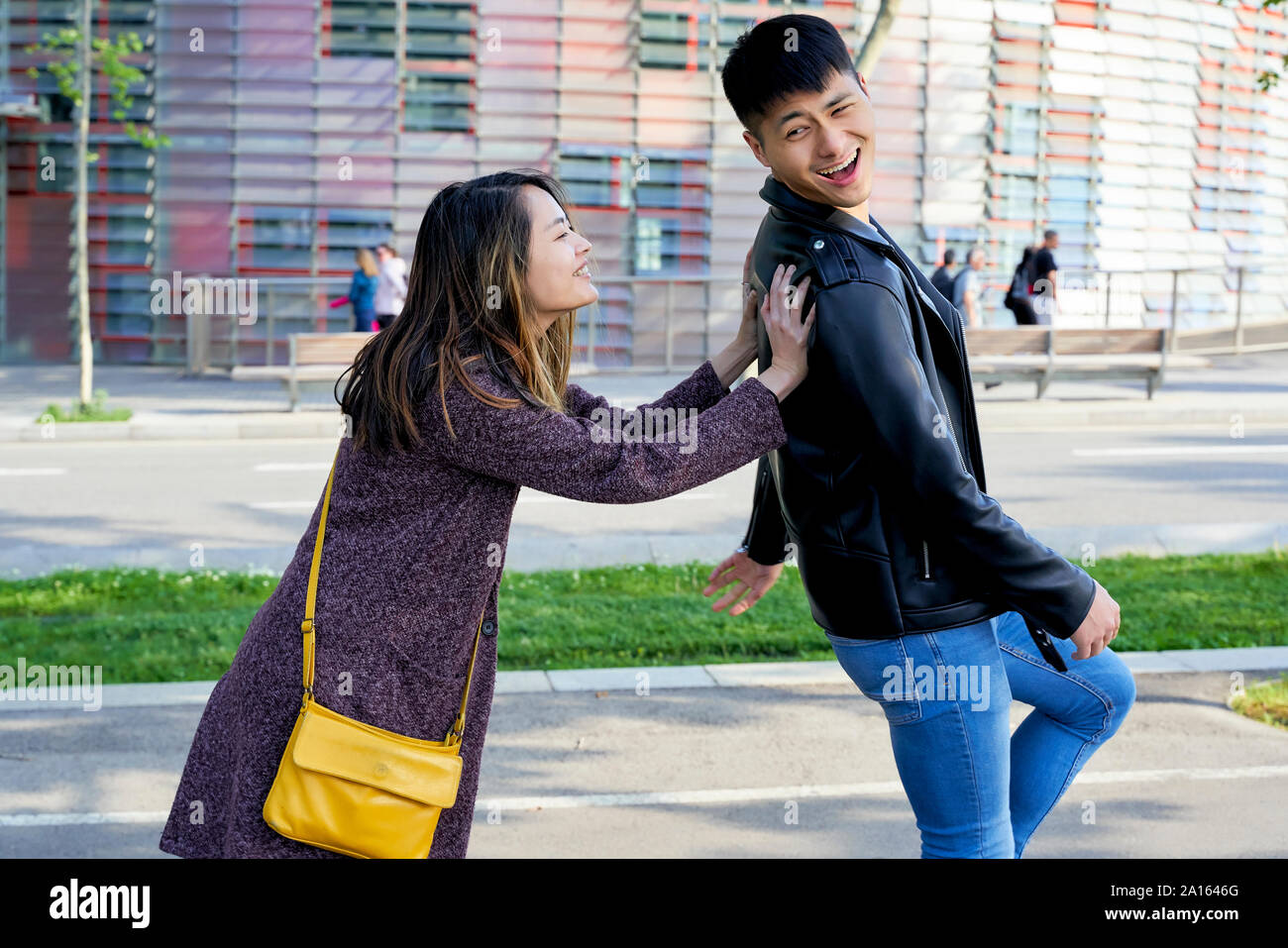Happy woman pushing boyfriend down the street, Barcelona, Spain Stock ...