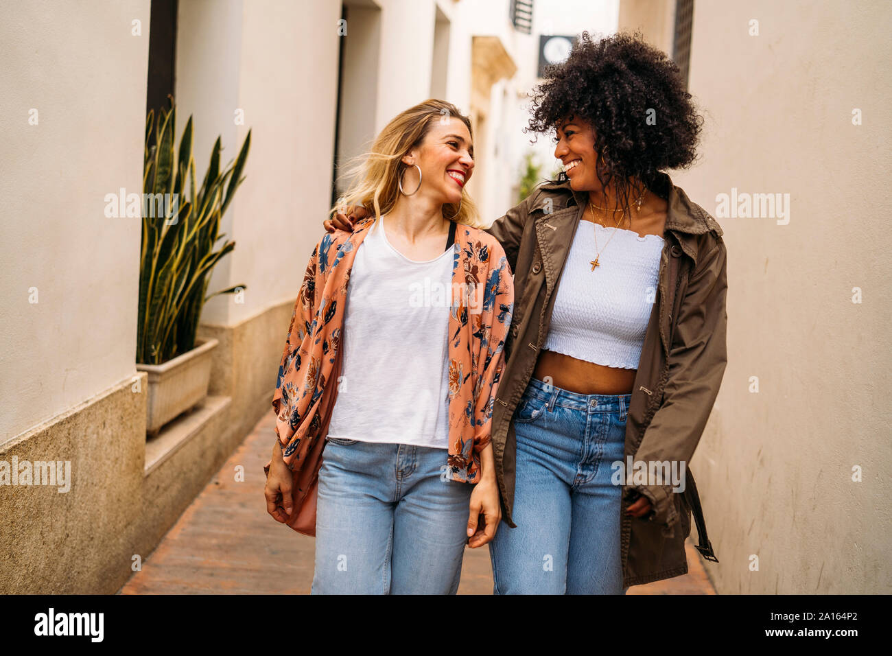 Multicultural laughing women walking in the city Stock Photo - Alamy