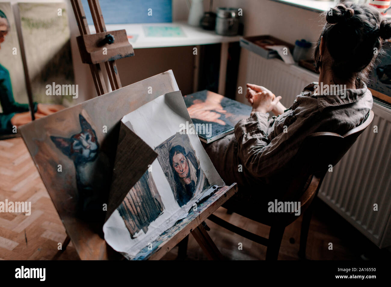 Female artist sitting in her studio with paintings Stock Photo - Alamy