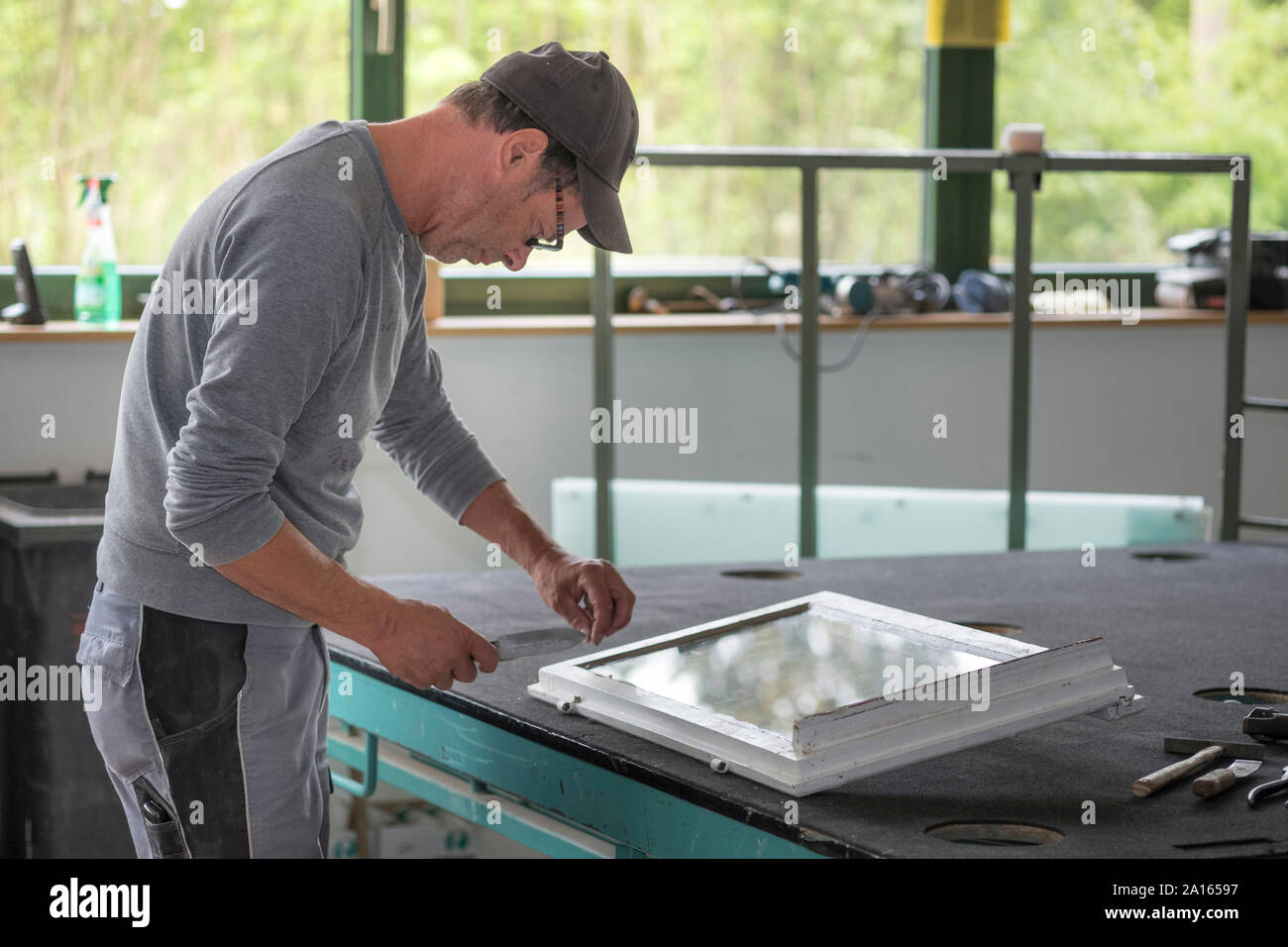 Glazing, glazier during work with tool on window frame Stock Photo - Alamy