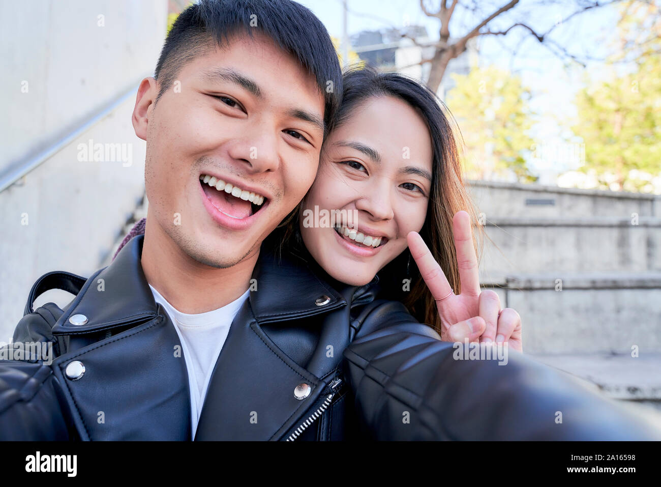 Portrait of happy young couple making victory sign Stock Photo - Alamy