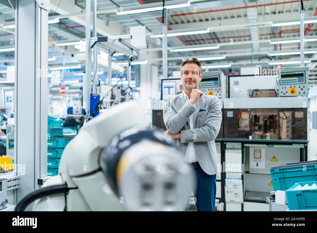 Portrait of confident businessman at assembly robot in a factory Stock ...