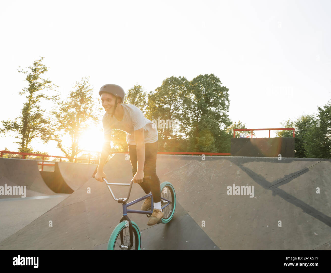 Happy young man riding BMX bike at skatepark at sunset Stock Photo - Alamy