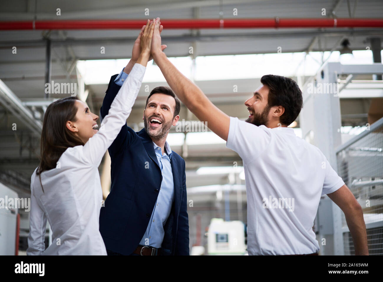 Happy businessman and employees high fiving in a factory Stock Photo ...