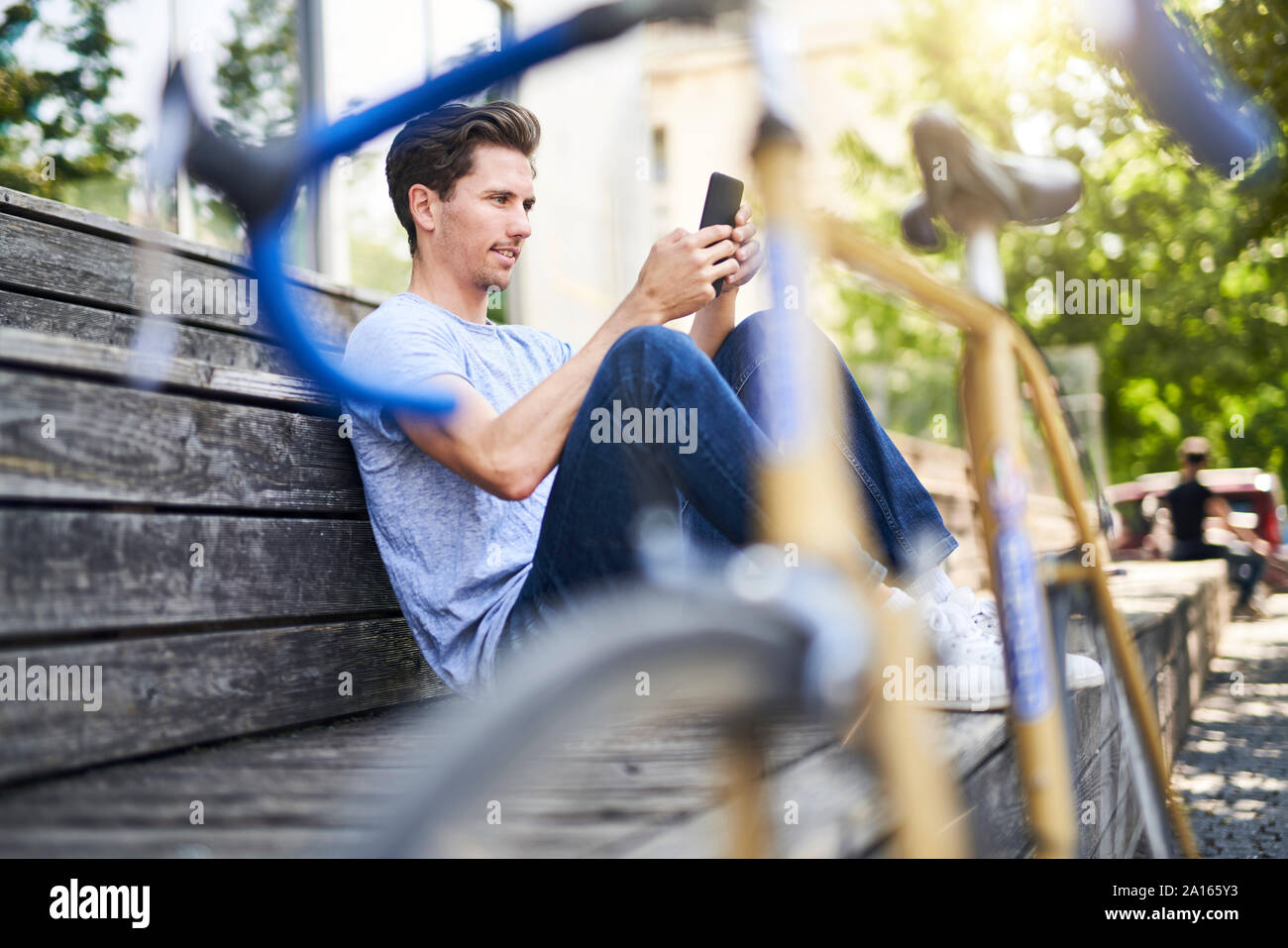 Man with racing cycle sitting on bench using smartphone Stock Photo - Alamy