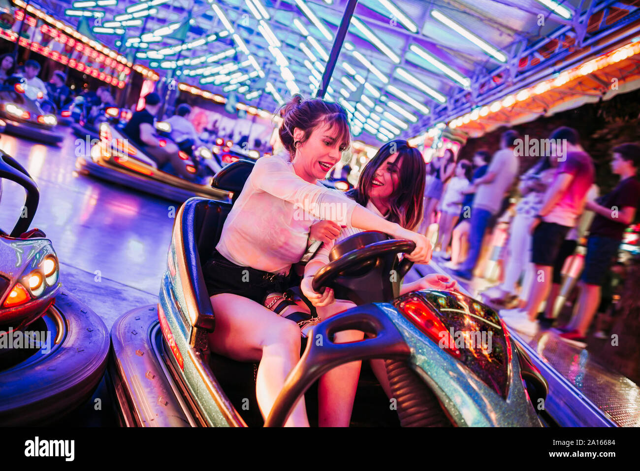 Two young women riding bumbper car on a funfair at night Stock Photo ...