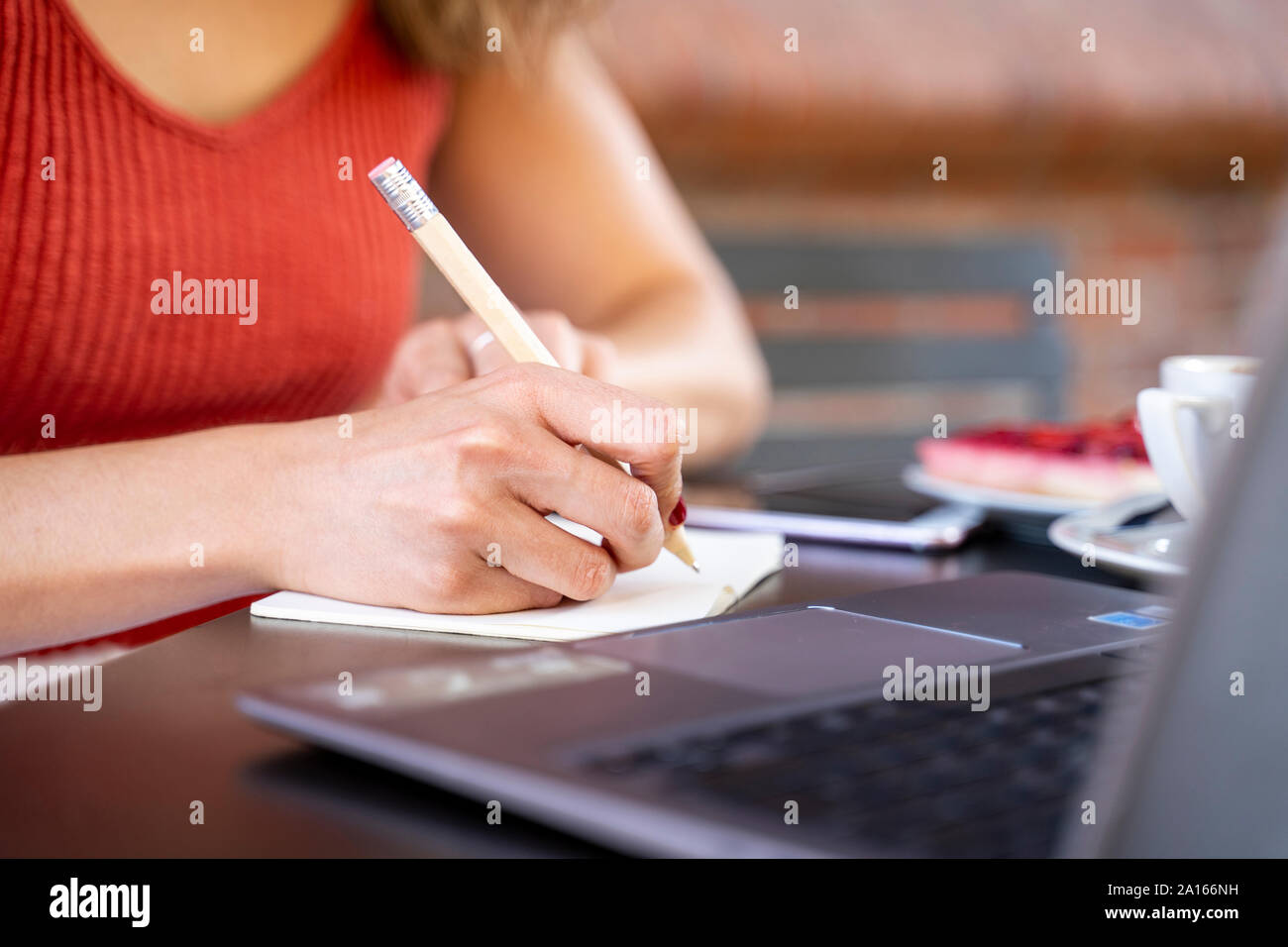 Young blogger sitting at street cafe taking notes hi-res stock ...