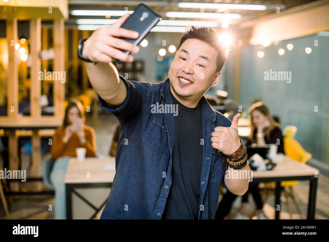 Stylish modern, cheerful Chinese man shooting self picture on front ...