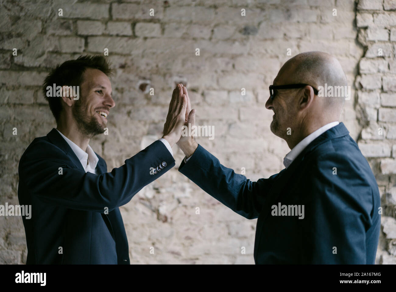 Senior and mid-adult businessman high fiving Stock Photo - Alamy