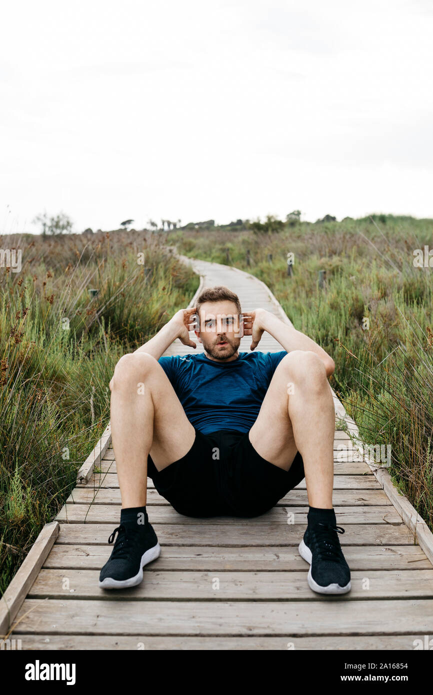 Jogger doing sit-ups on a wooden walkway Stock Photo - Alamy