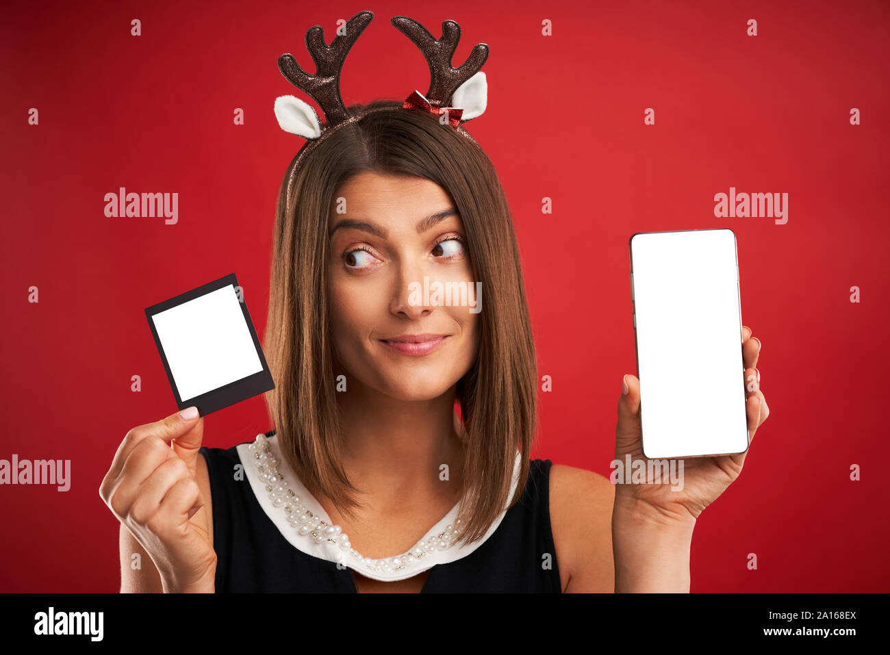 Woman In Christmas Mood Comparing Instant Pictures To Smartphone Camera