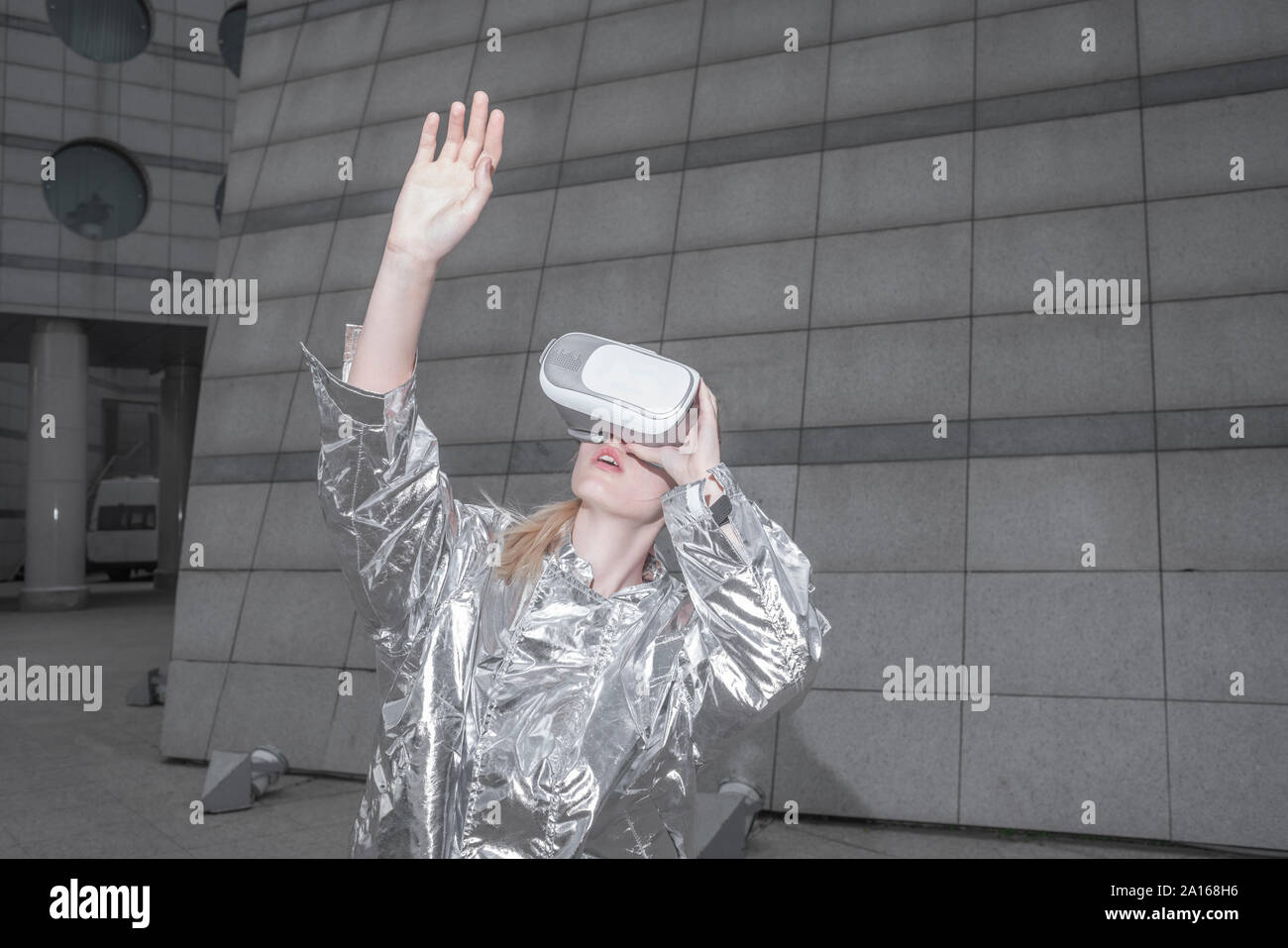 Girl in silver suit looking through VR goggles, watching her hand Stock ...