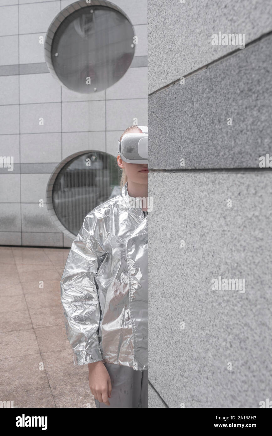 Girl in silver suit looking through VR goggles behind wall Stock Photo ...